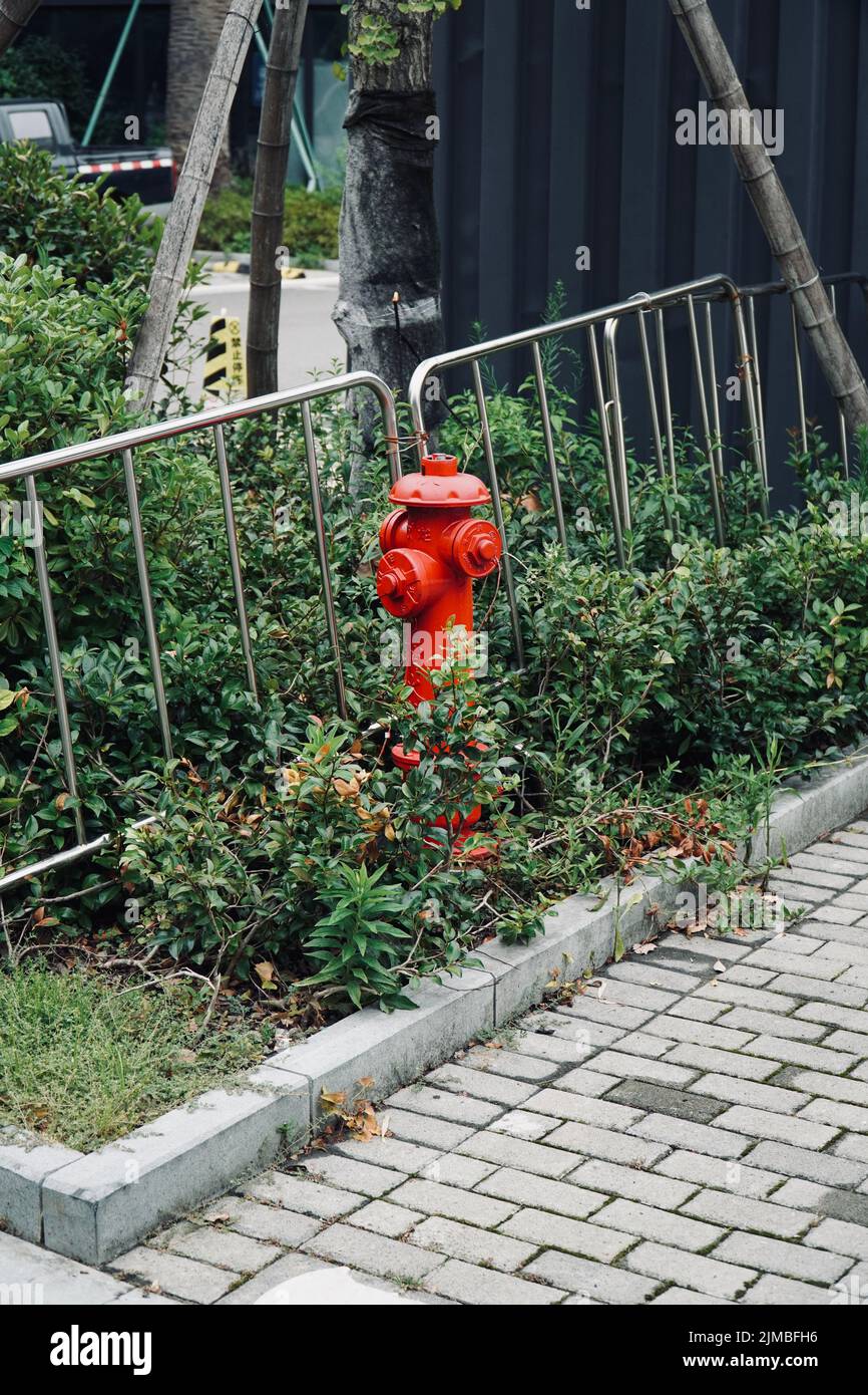 A vertical shot of a red water hydrant on a sidewalk Stock Photo - Alamy