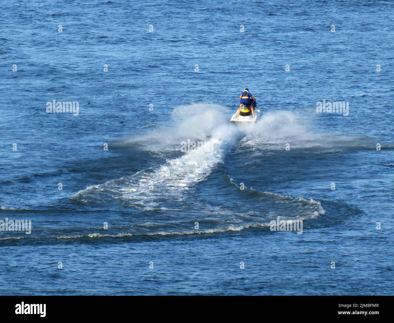 Man from behind on jet ski turns fast on the water Stock Photo - Alamy