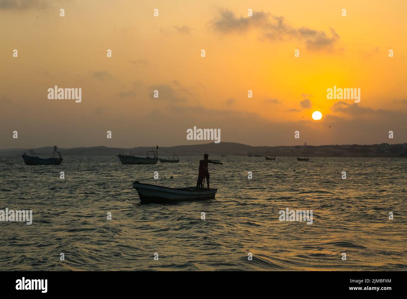 The fisherman on a boat against the background of a beautiful sunset Stock Photo - Alamy