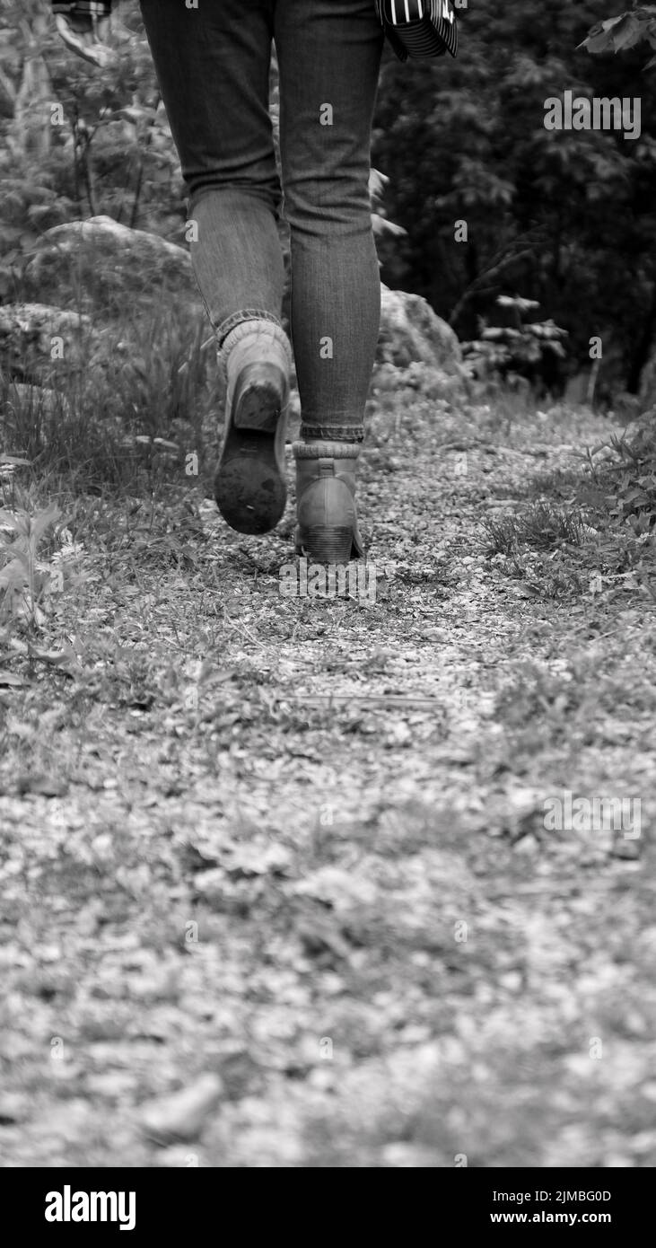 A back view of human feet walking through way surrounded by grass Stock ...