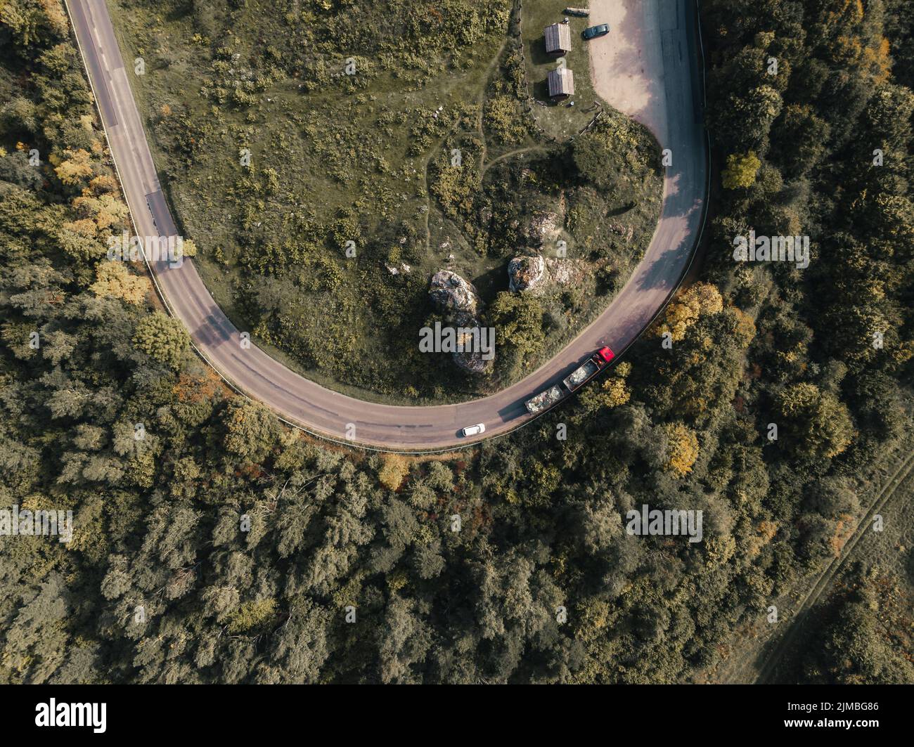 The aerial view of the curved road passing by the green forest Stock ...