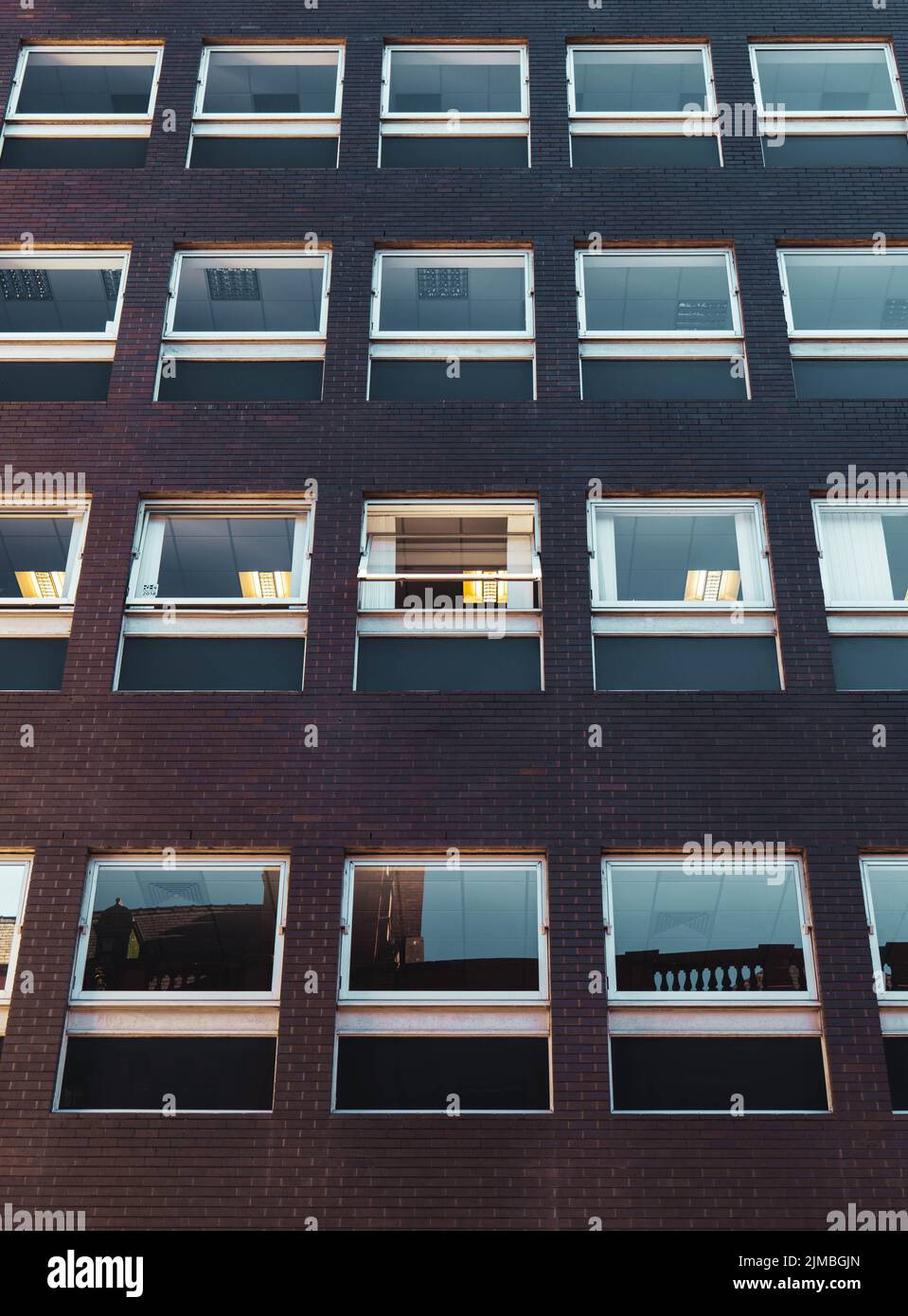 A vertical shot of glass windows of a modern apartment building with a ...