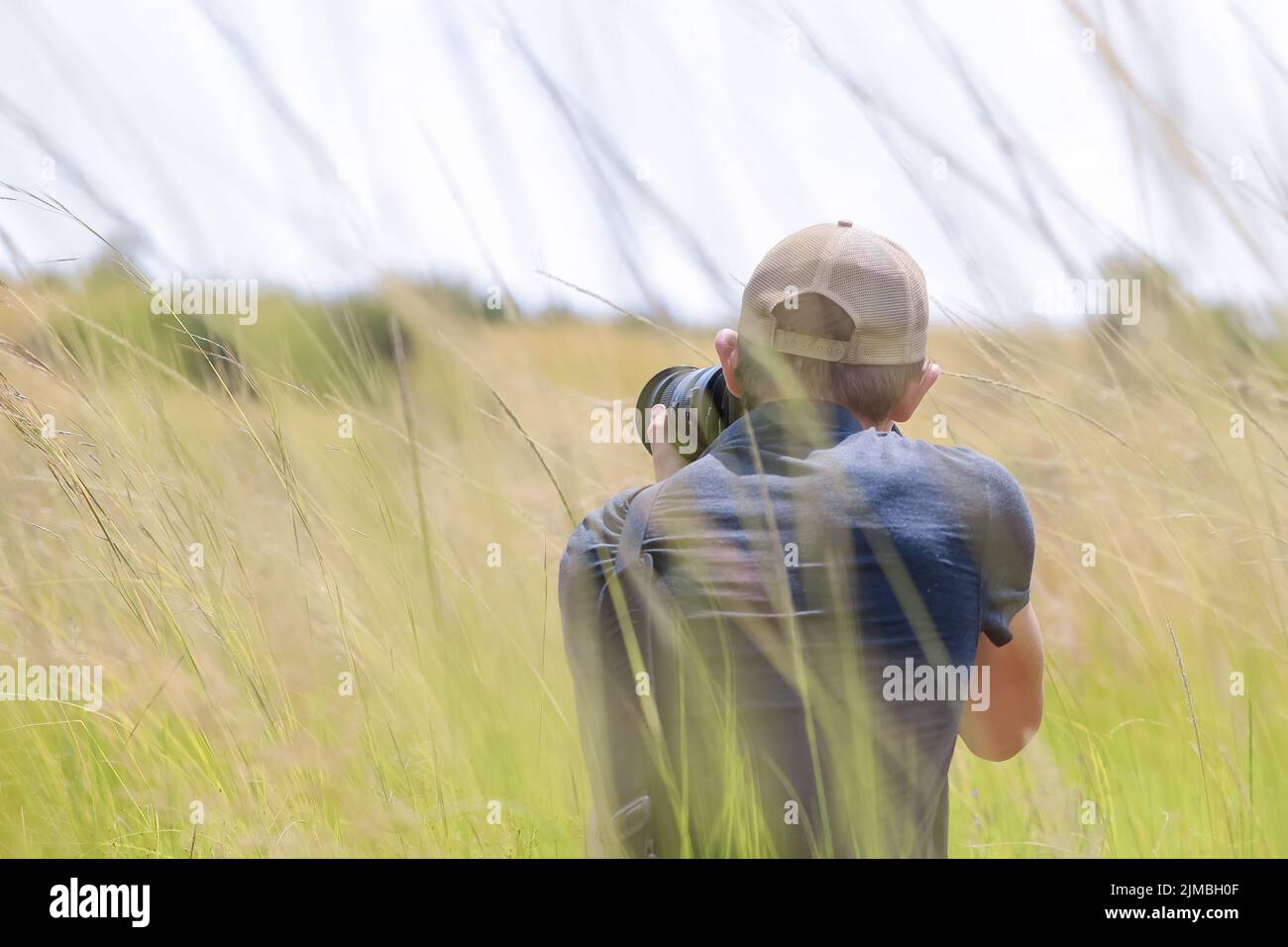A male photographer capturing nature in a field during daylight Stock ...