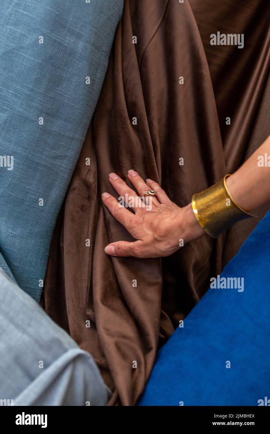 A woman's hand gently touching a brown clothing fabric, a vertical shot ...