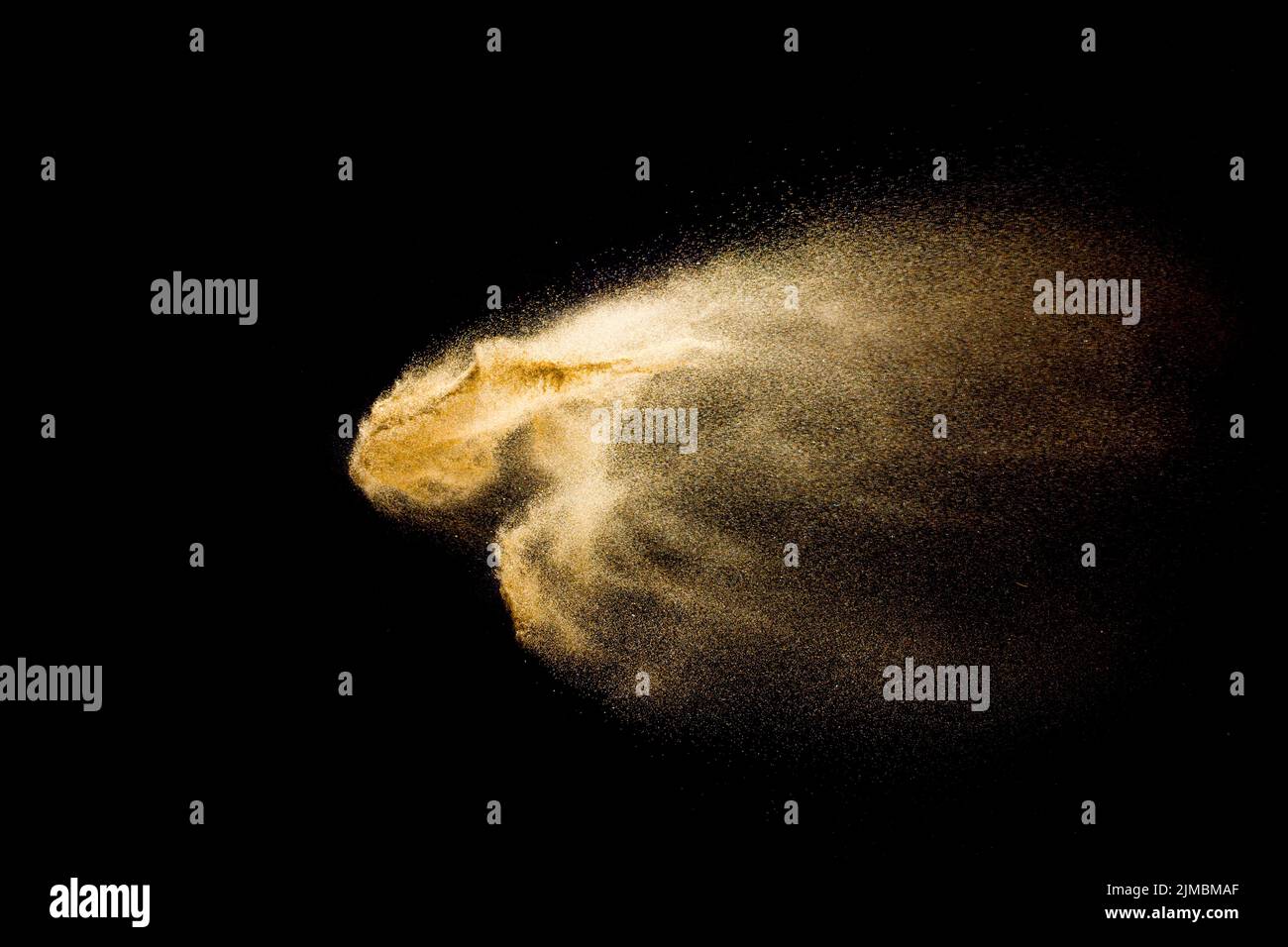 Abstract sand cloud. Golden colored sand splash against dark background ...
