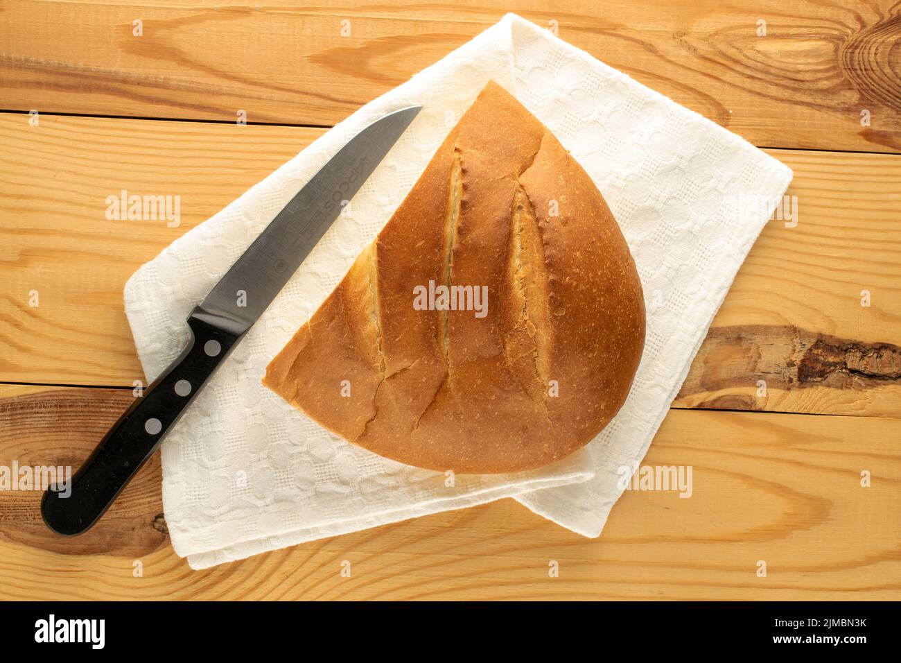 One half of a fragrant fresh loaf with a white linen napkin and a knife ...