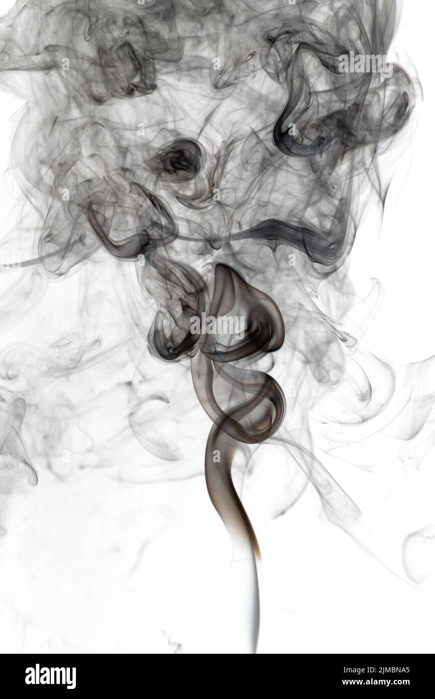 Puffs and curls of dark smoke on a white background rising from a ...