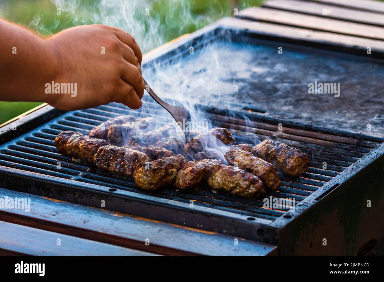 Preparing meat rolls called mici or mititei on barbecue. close up of ...