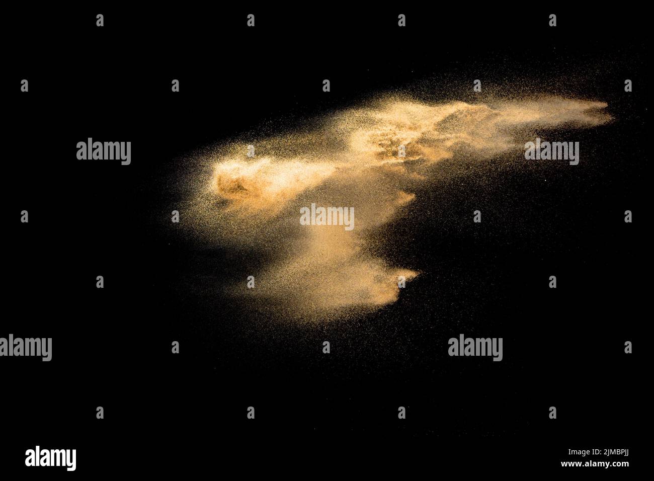 Golden colored sand splash against dark background. Yellow sand fly ...