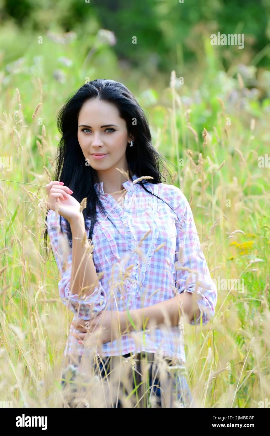 The beautiful woman in field with flower Stock Photo - Alamy