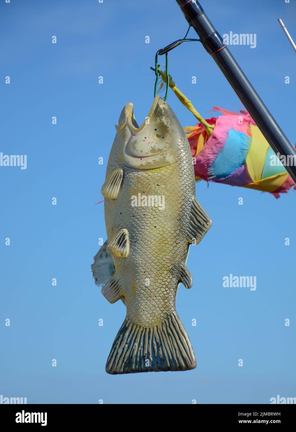 Plastic fish hanging on hook in the blue sky background Stock Photo - Alamy