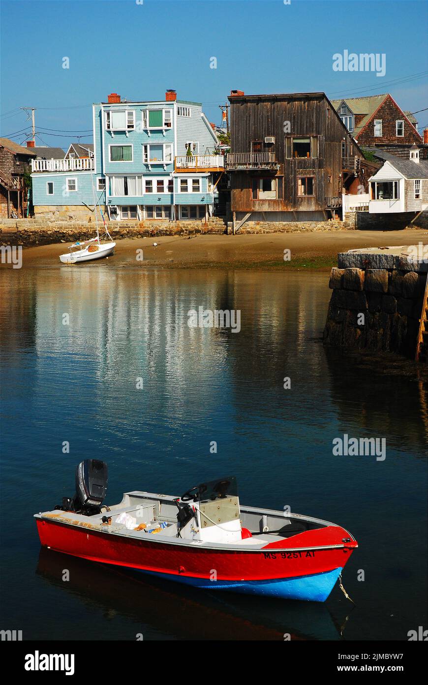 A red and blue boat is moored near the waterfront homes of Rockport, a ...