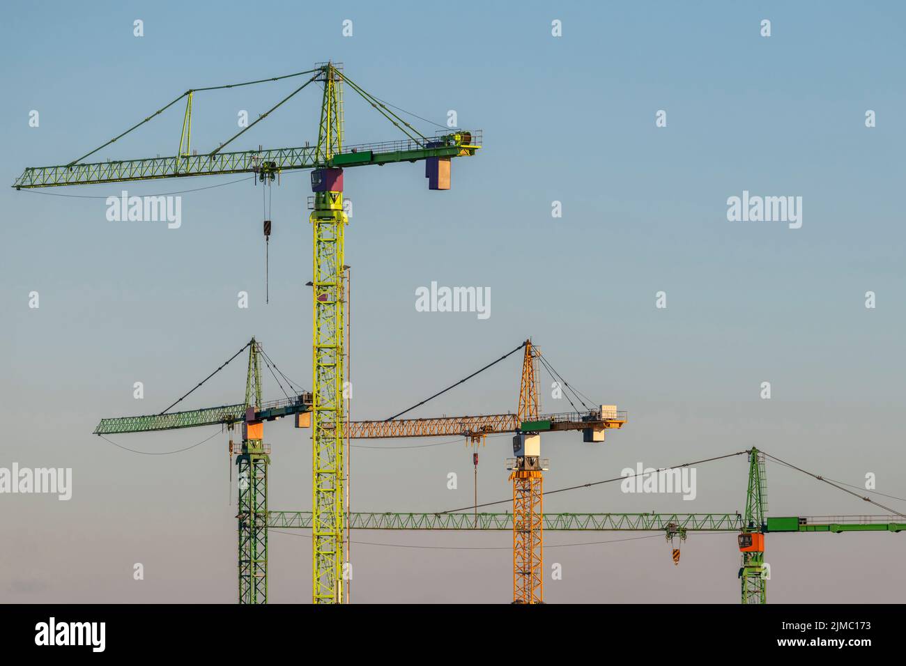 Colorful tower cranes in the evening light Stock Photo - Alamy