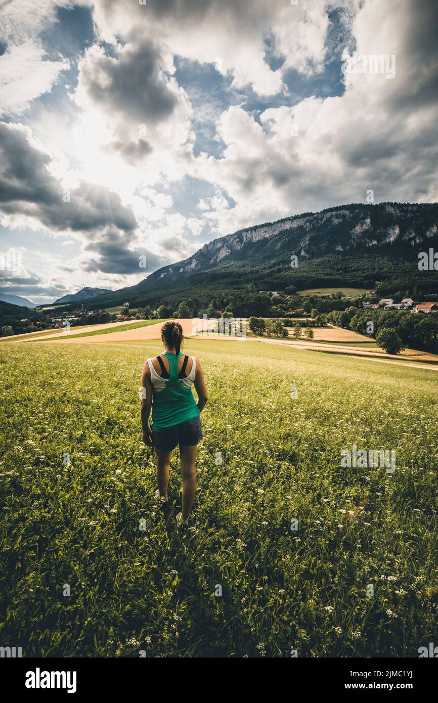 Young woman walking on summer meadow at sunny day, rear view. Image ...
