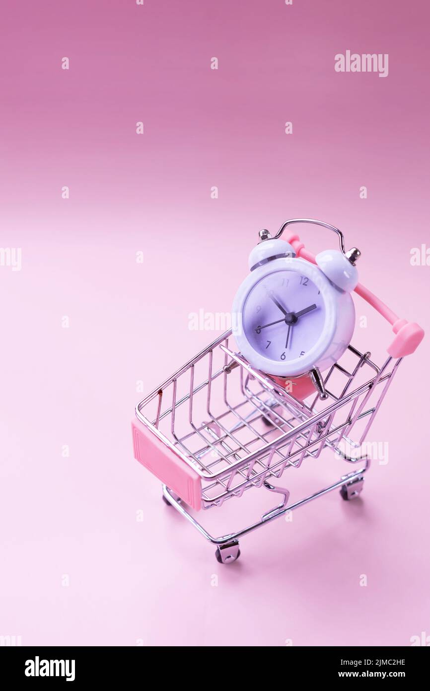 Black alarm clock and toy shopping cart isolated on white. watch in the ...