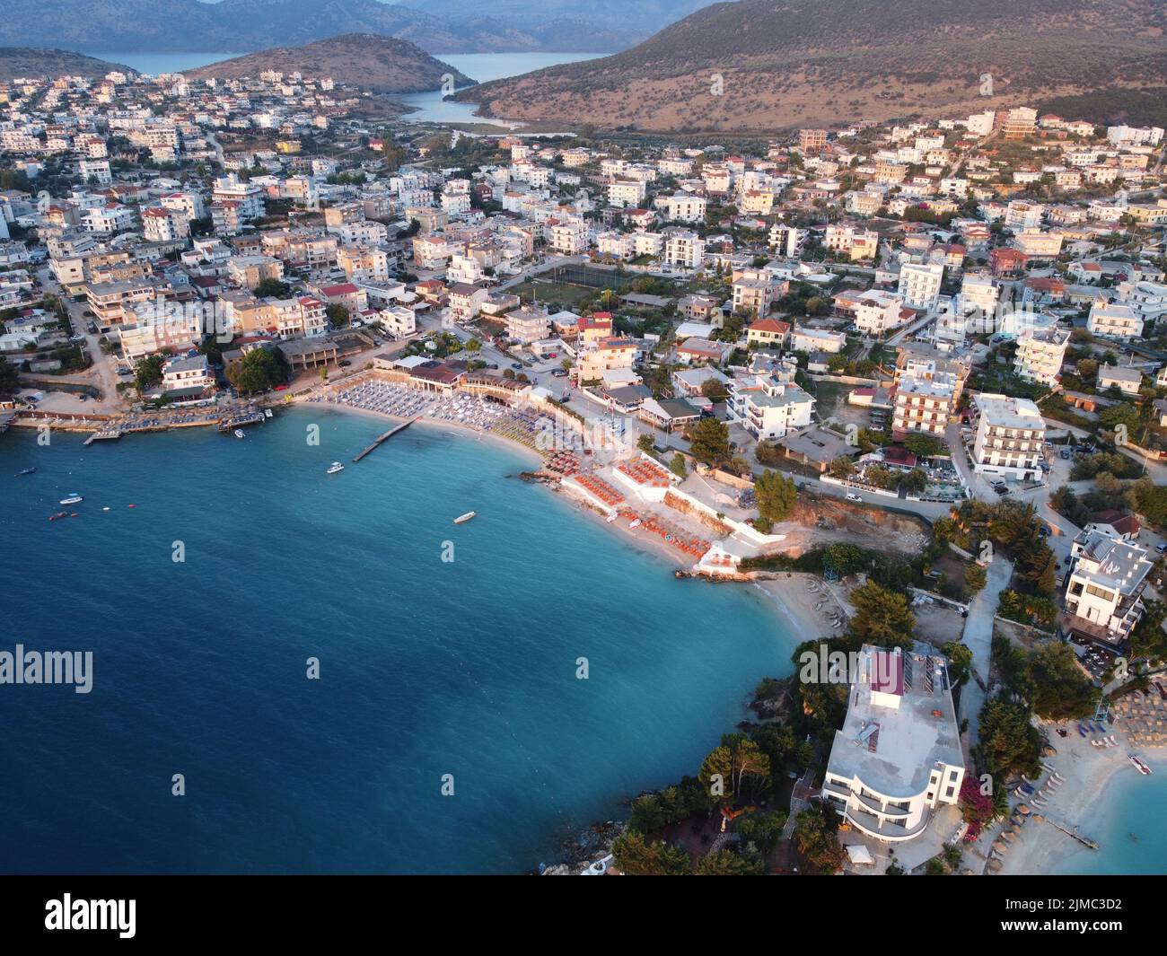 A drone view of a small town with buildings and a sandy beach near a ...
