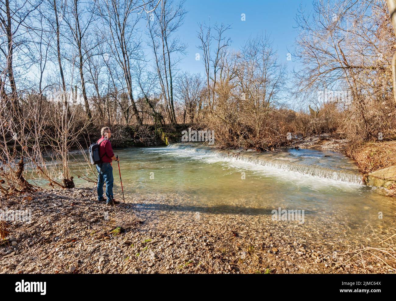 Hiker of about 60 years, on the bank of the stream Stock Photo - Alamy