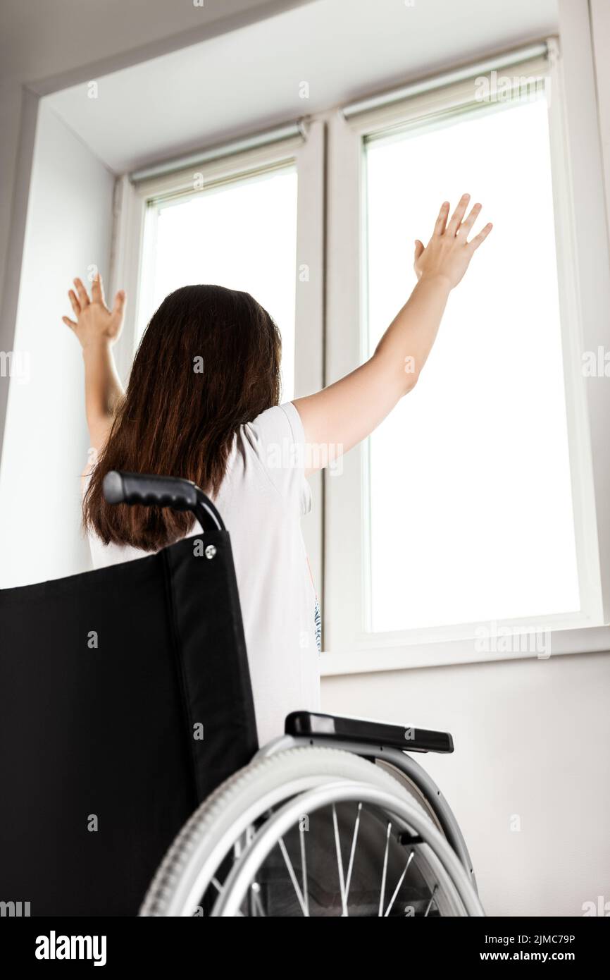 Invalid or disabled woman sitting wheelchair looking window daylight ...