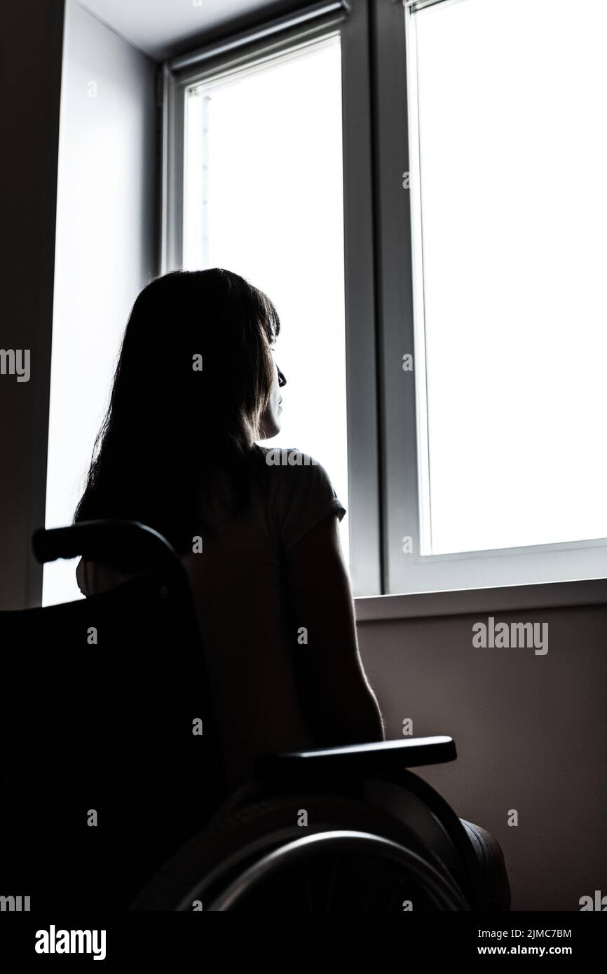 Invalid or disabled woman sitting wheelchair looking window daylight ...