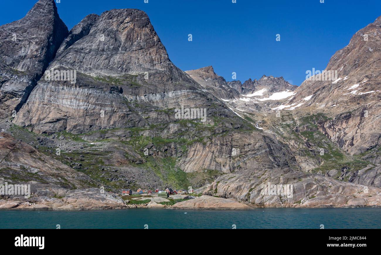 Remote settlement of Aappilattoq dwarfed by snow capped mountains in ...