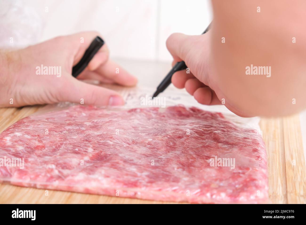 A man signs with a marker the date of production and a gram of minced ...