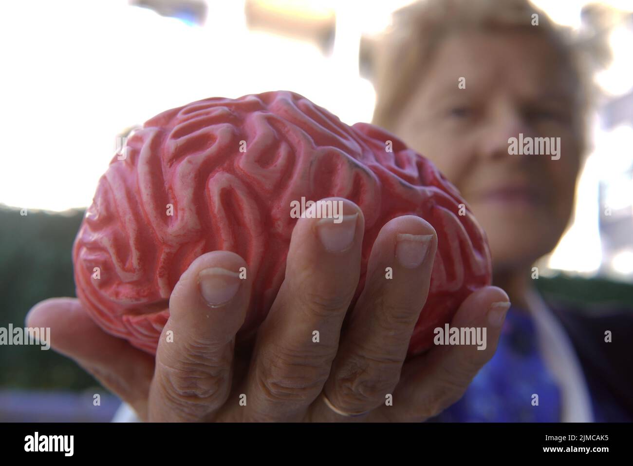 An elderly lady with a rubber brain looks at the camera Stock Photo - Alamy