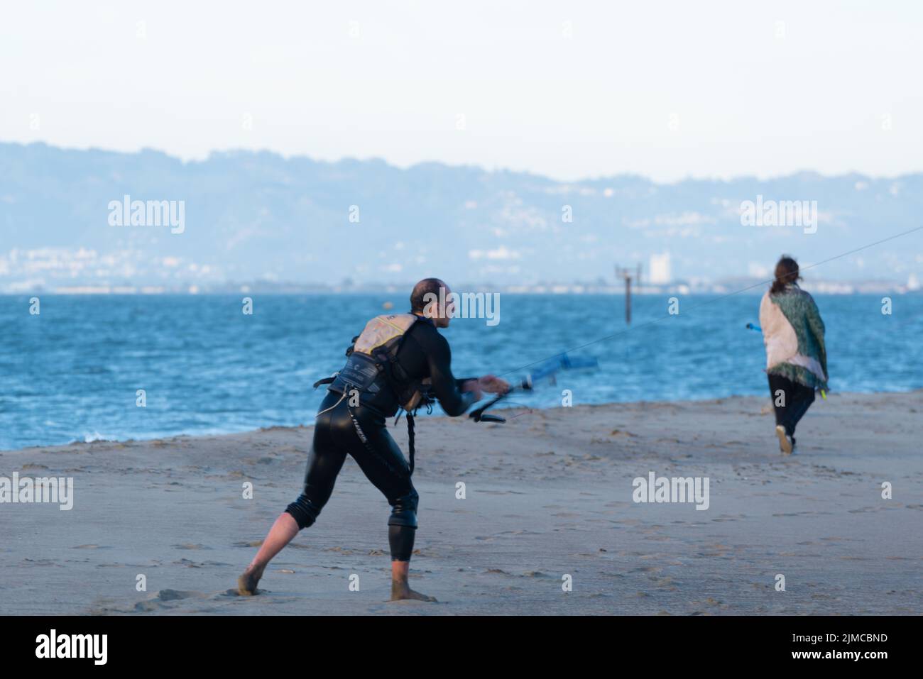 Blue water beach and kitesurfer pulling in his kite after his ride ...