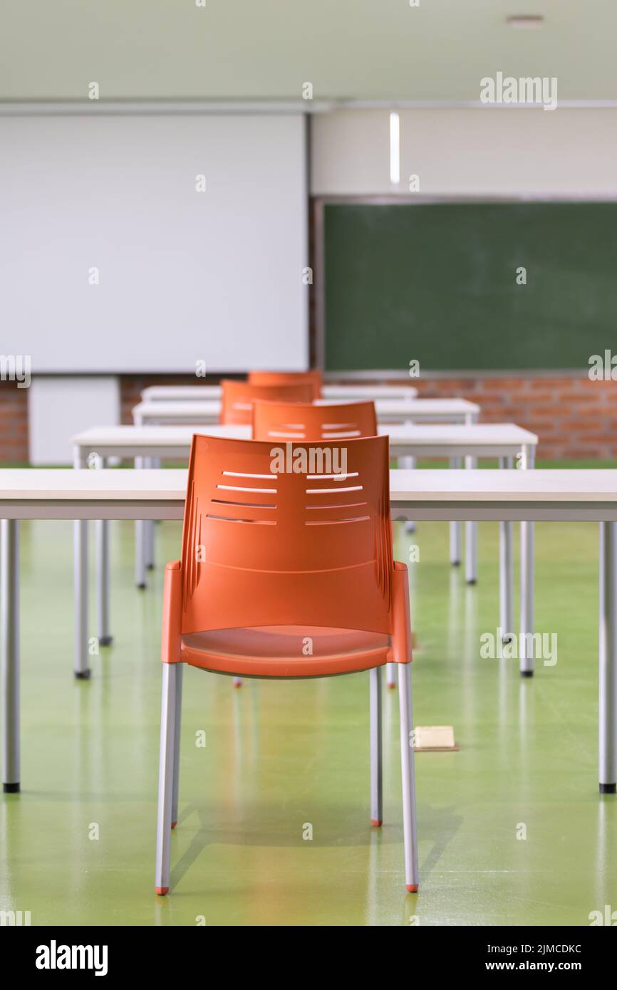 interior of a classroom in a school with desks, chairs and blackboard ...