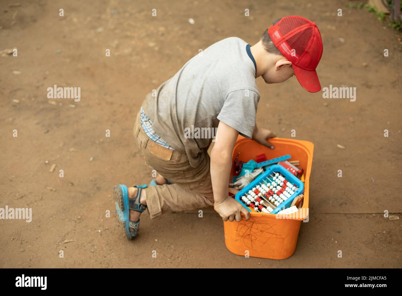 Child collects toys from ground. Boy puts his things in drawer ...