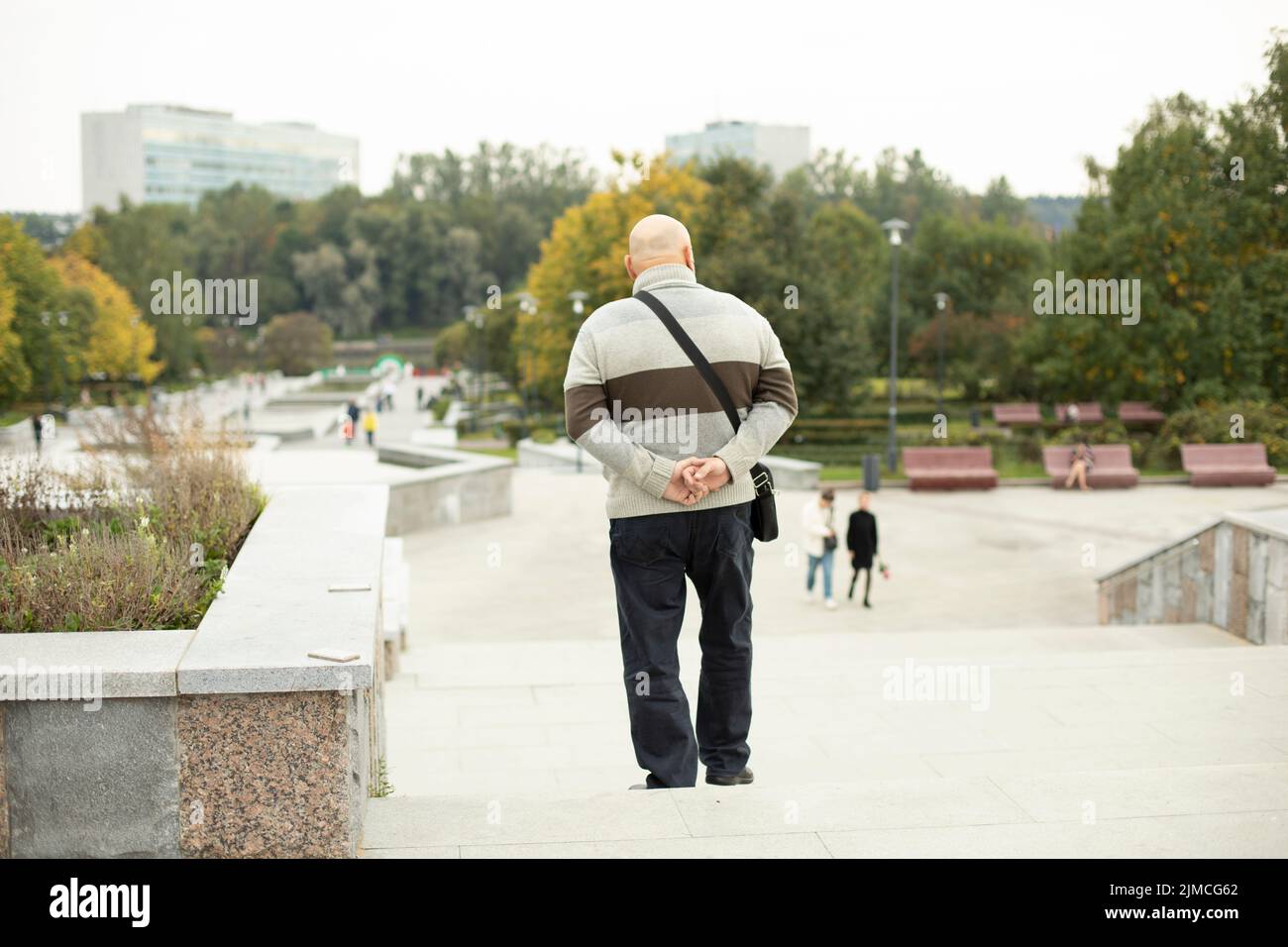 Pensioner in Russia walks around city in summer. Old man has his hands ...