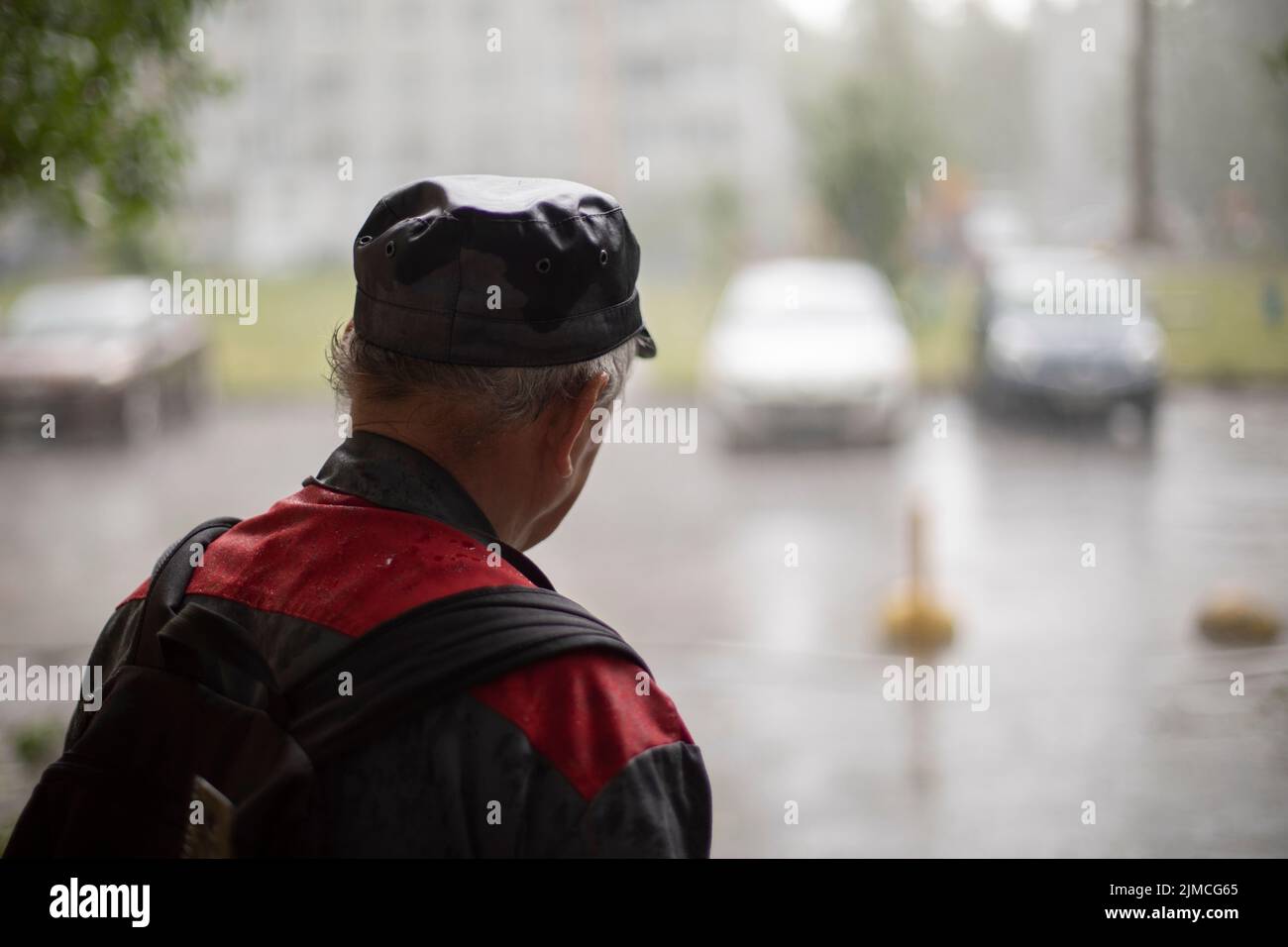 A man looks at the rain. An old man in a cap in bad weather. A ...