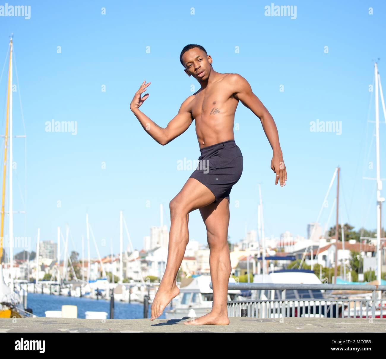 Attractive dancer at an outdoor scene against a blue sky and a backdrop ...