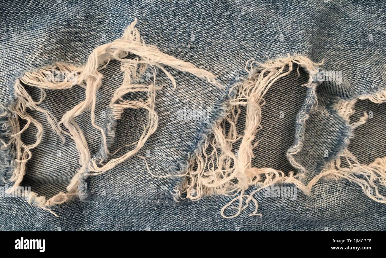 Ripped denim jeans background. Texture of denim or blue jeans ...