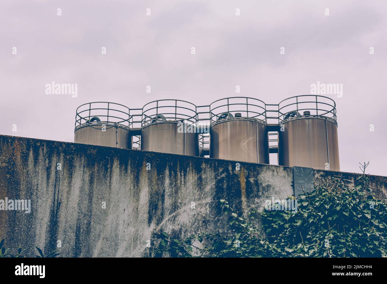Four industrial metal storage tanks above a wall Stock Photo - Alamy