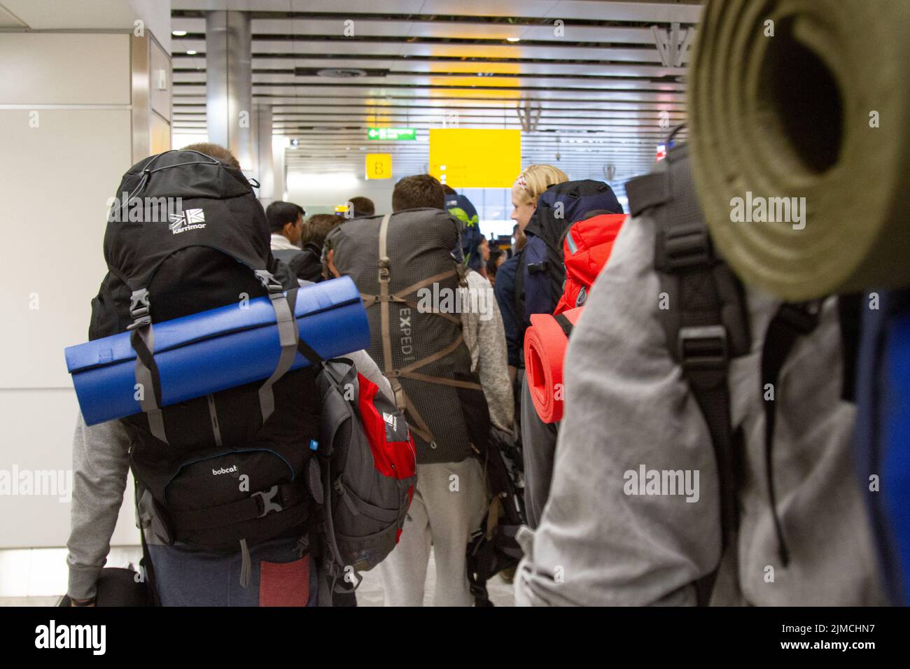 Backpackers walking through an airport at the start of an expedition ...