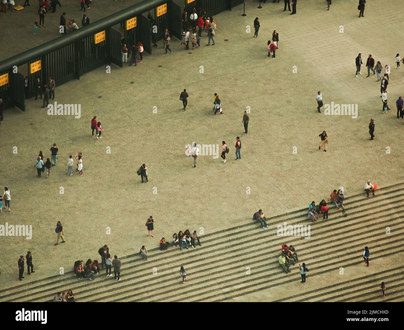 Stone plaza with entrances and exits many people walking and sitting ...