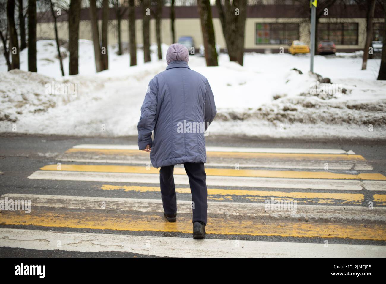 Woman crosses road on zebra. Pensioner in Russia walks down street. Man ...