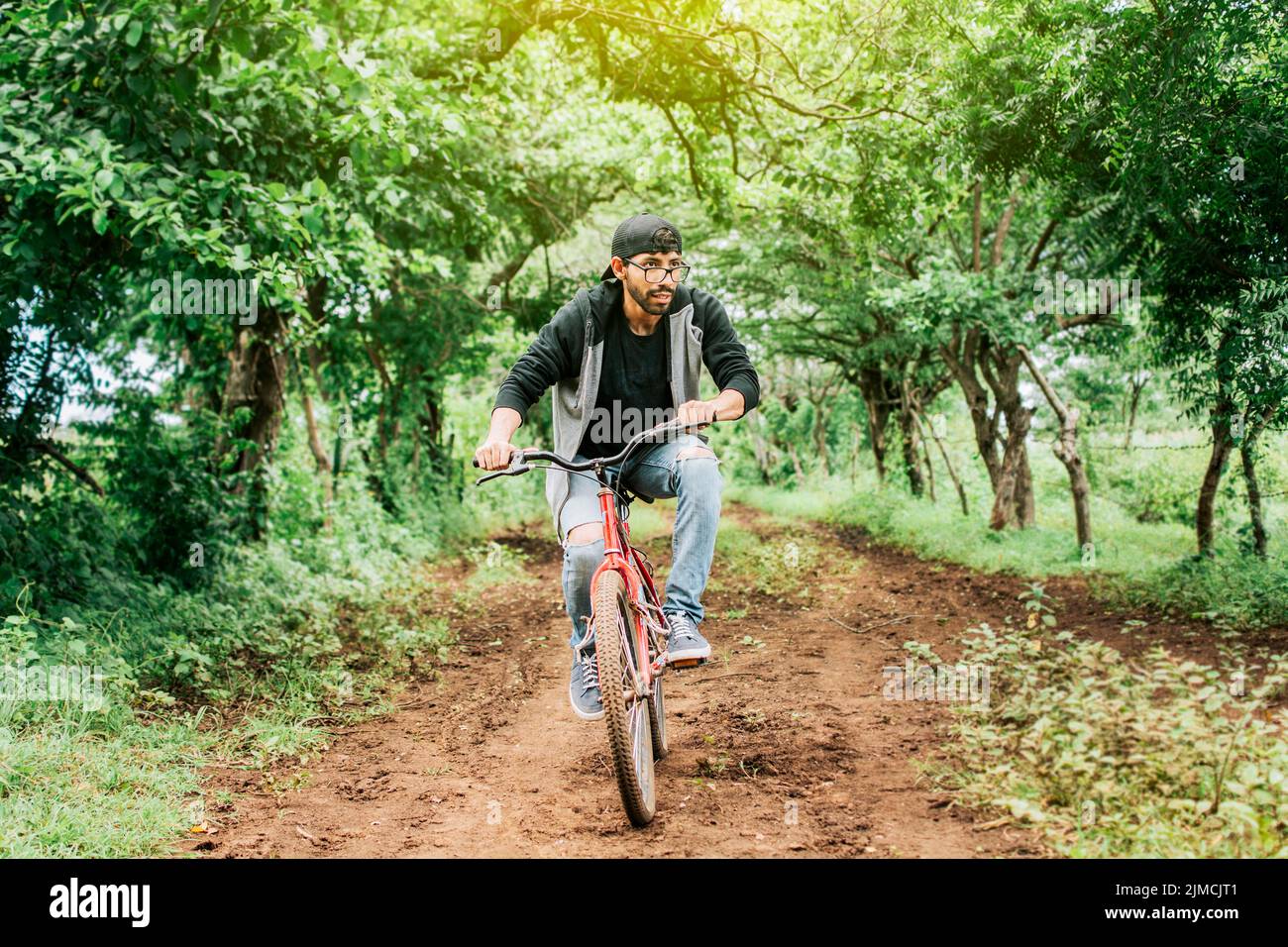 Teenage guy riding a bike in the countryside, Portrait of a guy in cap ...