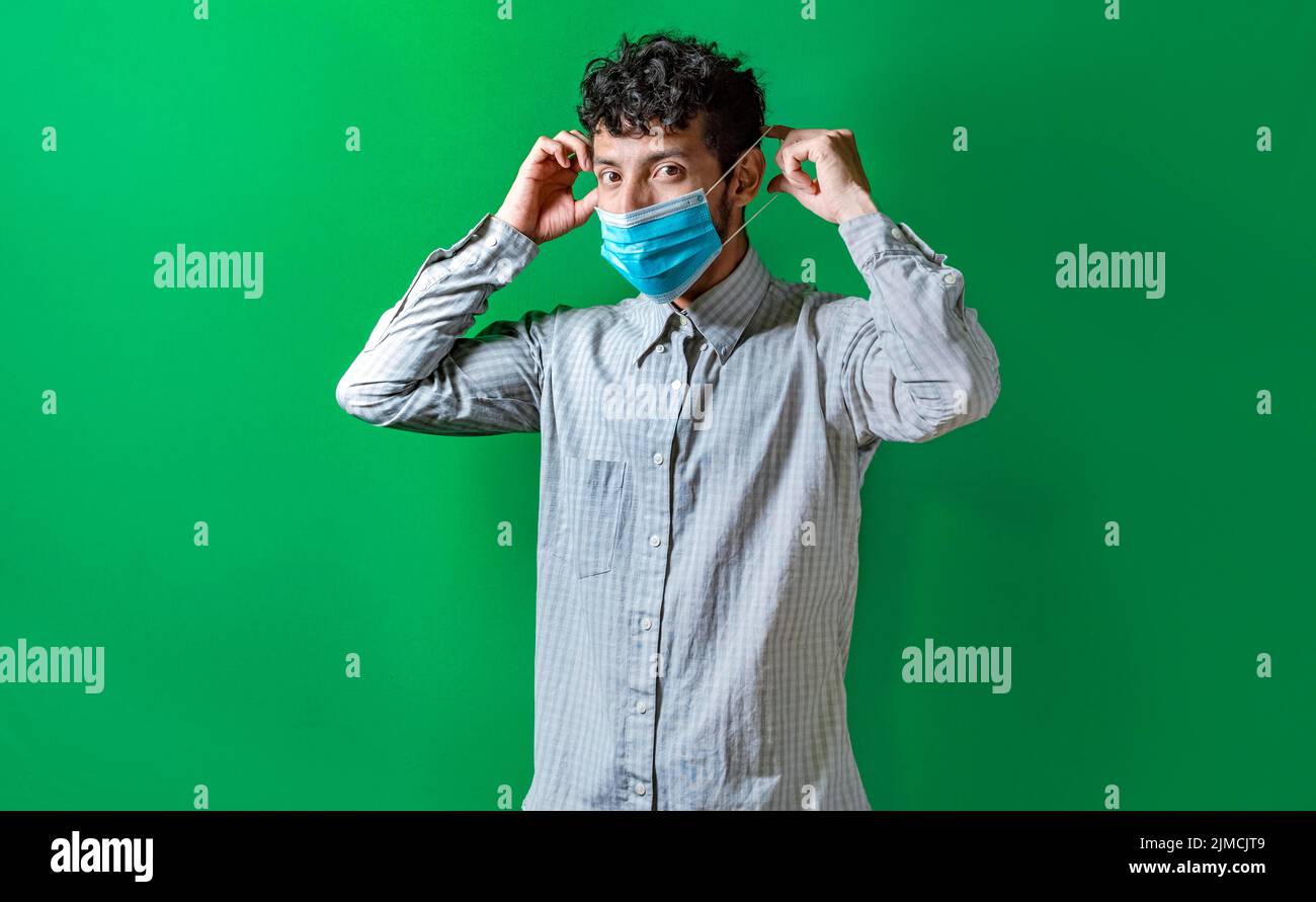A man putting on the mask on isolated background, Handsome man putting ...