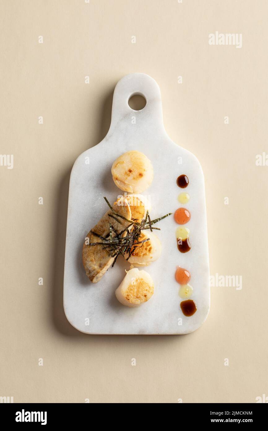 From above of tasty fried scallops with foie gras served on marble ...