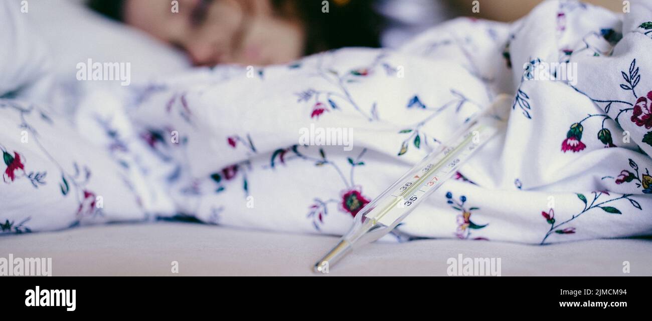 Woman in bed with fever focus on thermometer coronavirus or COVID-19 ...