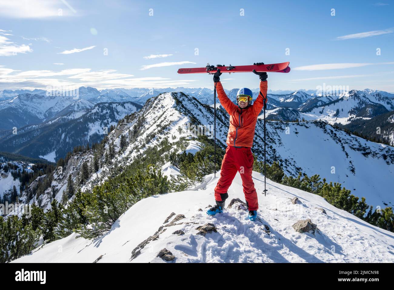 Ski tourer lifts his skis into the air at the summit of Jagerkamp ...