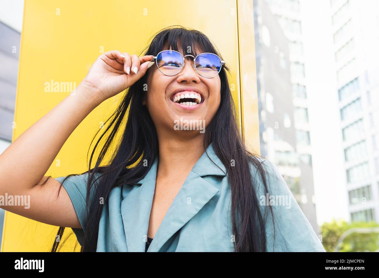 Low angle of happy young Asian female with long hair adjusting stylish ...