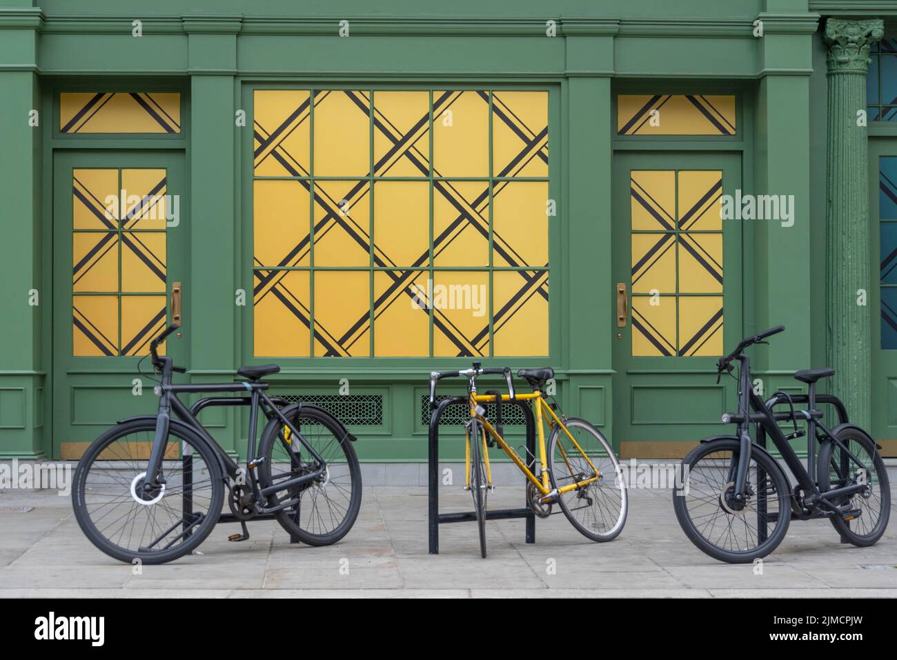 Three bicycles, green-yellow building facade, Kensington district ...