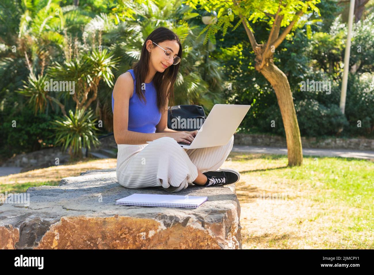 Side view of focused full body of female student typing on netbook ...