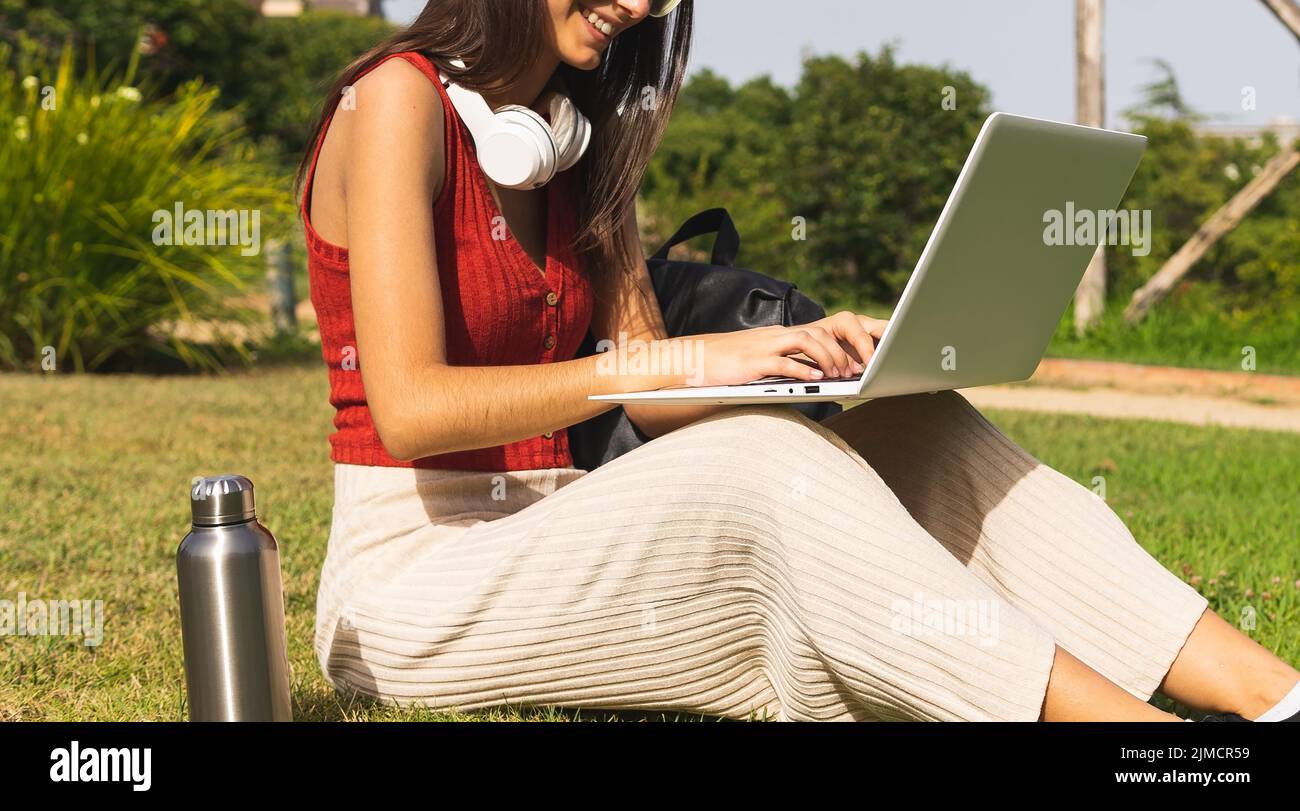 Side view of anonymous female student typing on netbook while doing ...