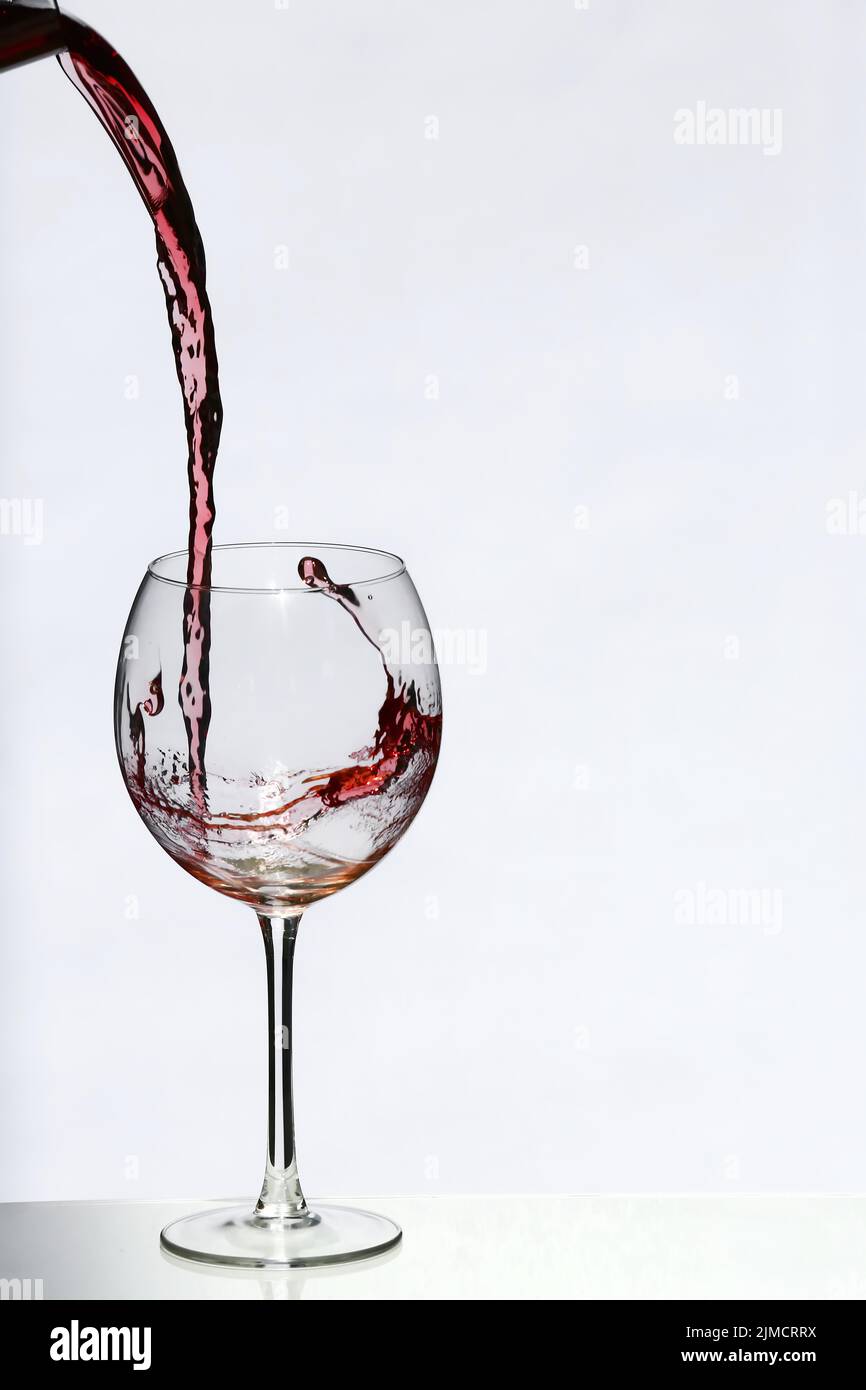 Pouring a glass of red wine. Released against a white background Stock ...