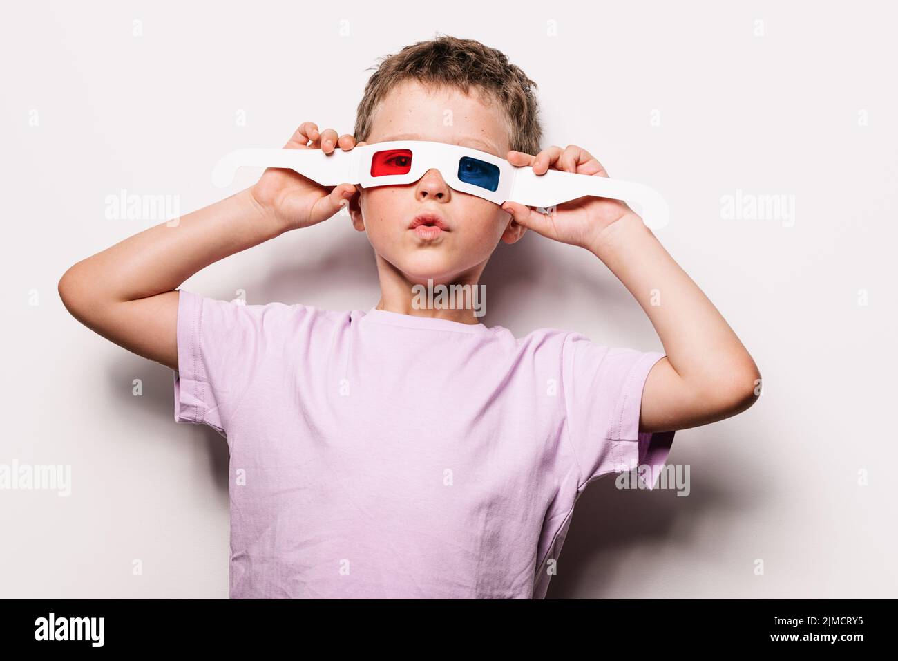 Cute boy in casual wear putting on 3D glasses with colorful lenses ...