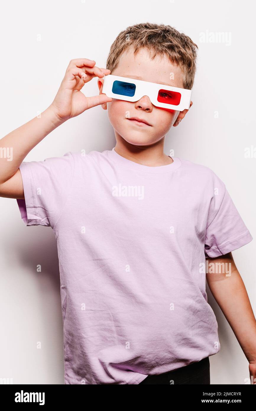 Cute boy in casual wear putting on 3D glasses with colorful lenses ...