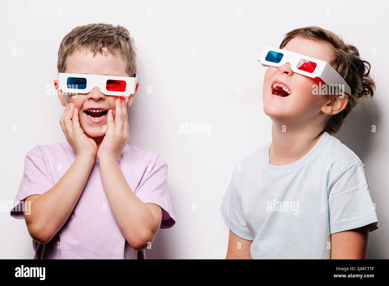 Amazed children in casual wear and 3D glasses touching cheeks with ...